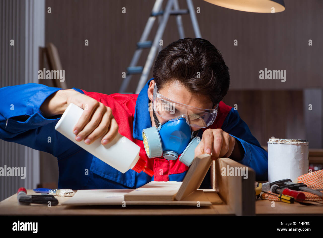 Young man gluing wood pieces together in DIY concept Stock Photo - Alamy