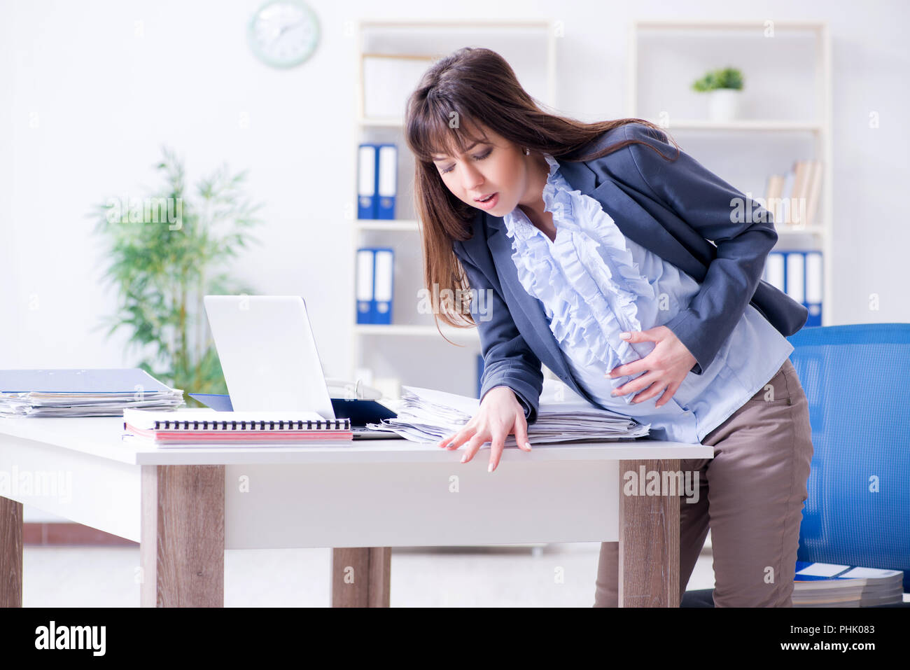Pregnant woman struggling to do work in office Stock Photo - Alamy
