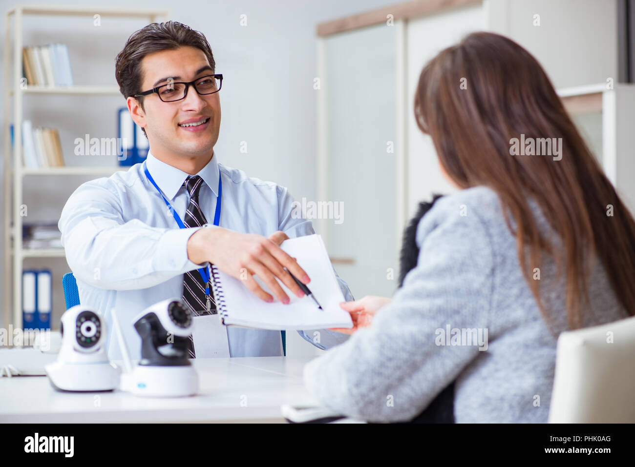 Sales assistant showing cameras to client in shop Stock Photo - Alamy