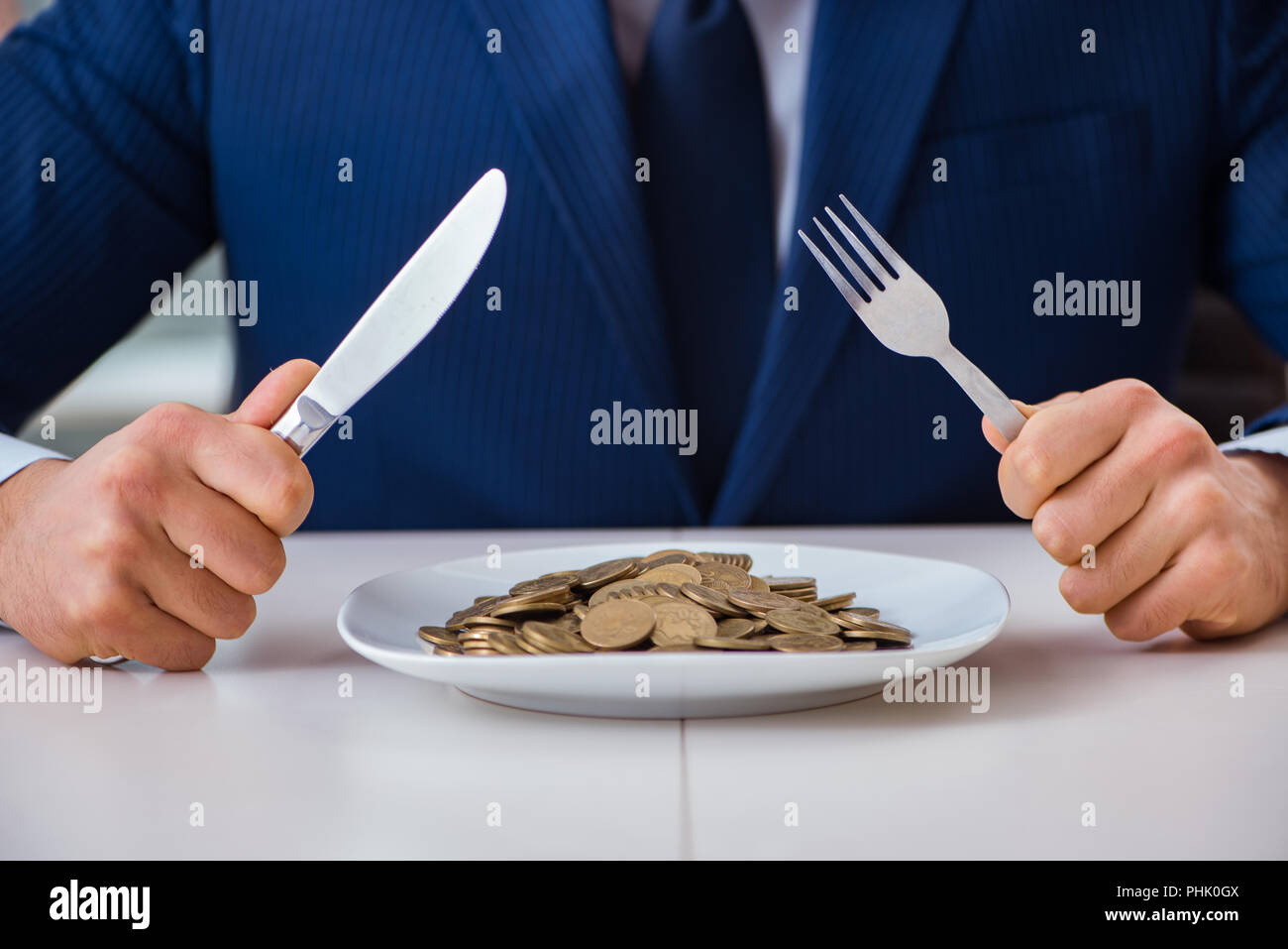 Funny businessman eating gold coins in office Stock Photo - Alamy