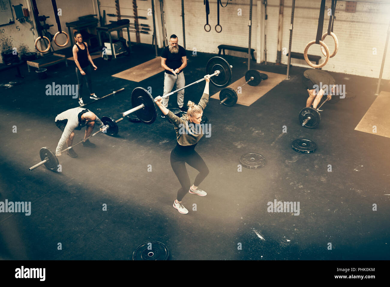 High angle of a group of fit people lifting weights together during an ...