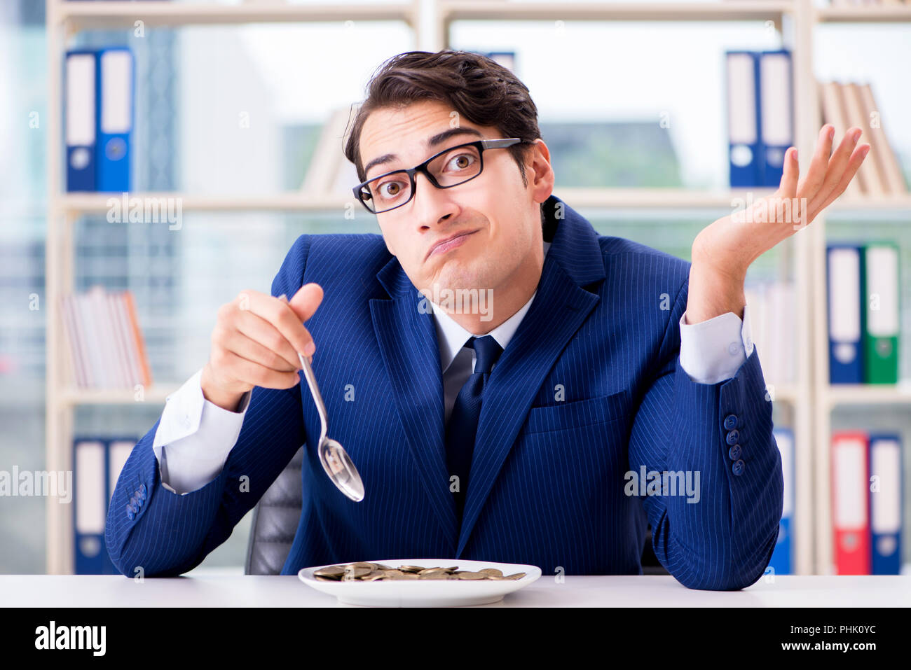 Funny businessman eating gold coins in office Stock Photo - Alamy