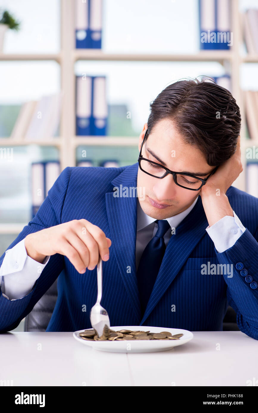 Funny businessman eating gold coins in office Stock Photo - Alamy