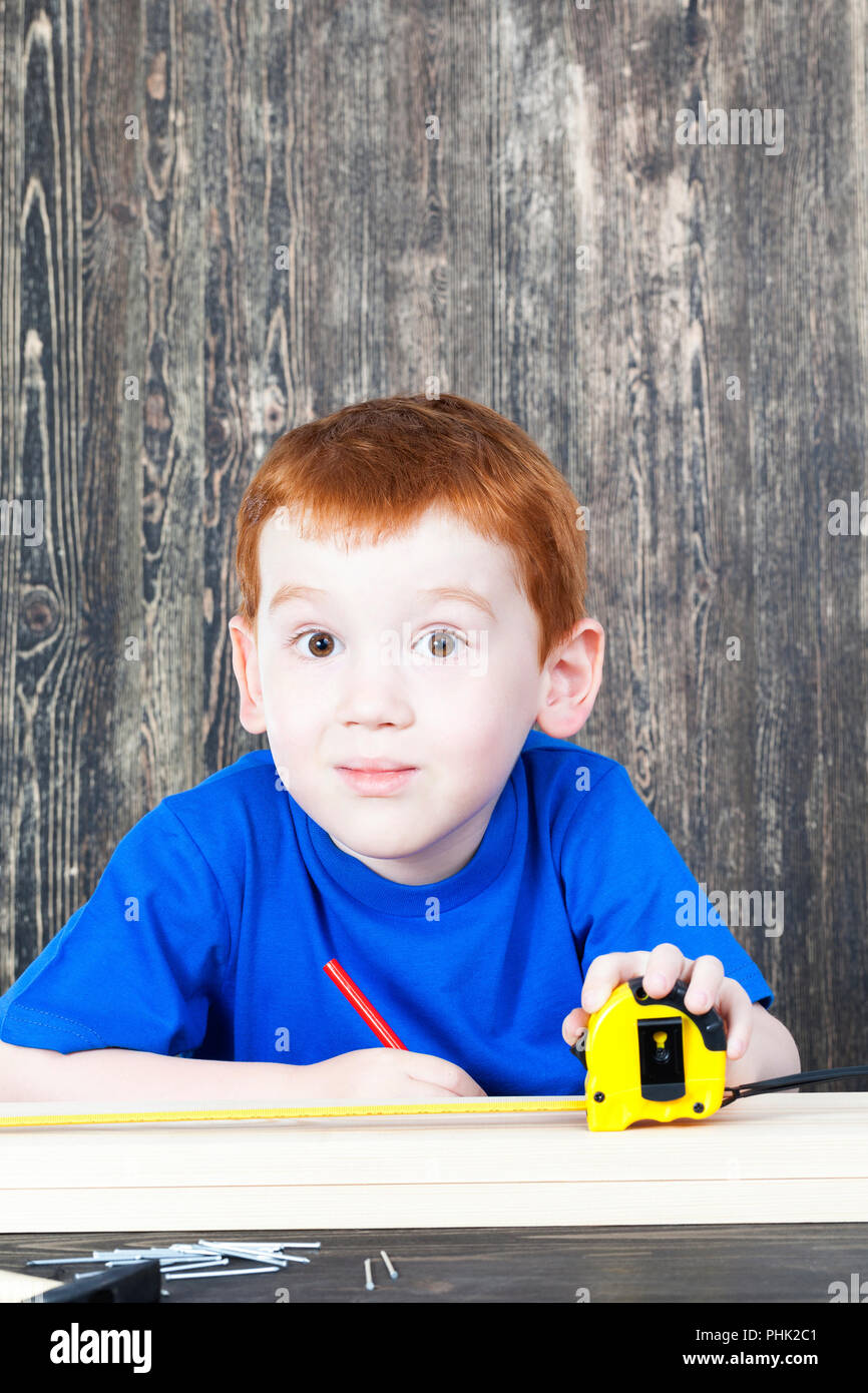 a red-haired boy looks at the camera measuring and sizes the ruler, a ...