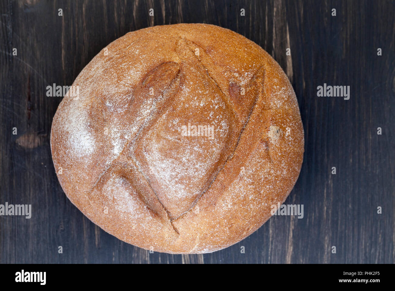 fresh round loaf of rye dark bread on a black table, closeup, top view ...