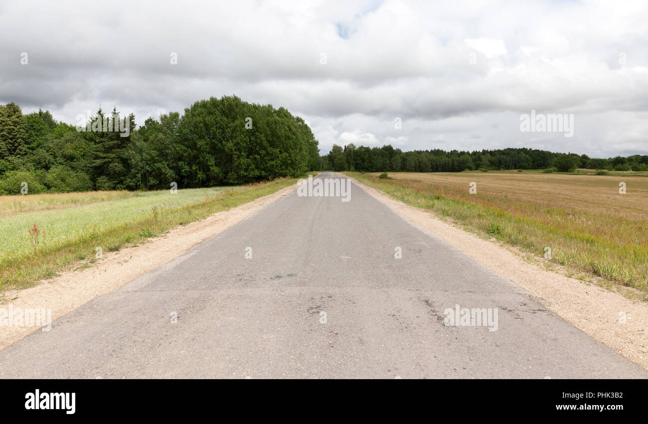 old dusty paved road in the countryside in dusky weather, grass and ...