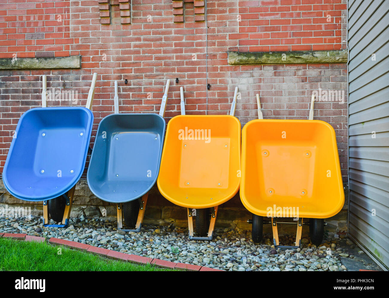 Four wheelbarrows, 2 yellow, 2 blue leaning against a wall Stock Photo ...