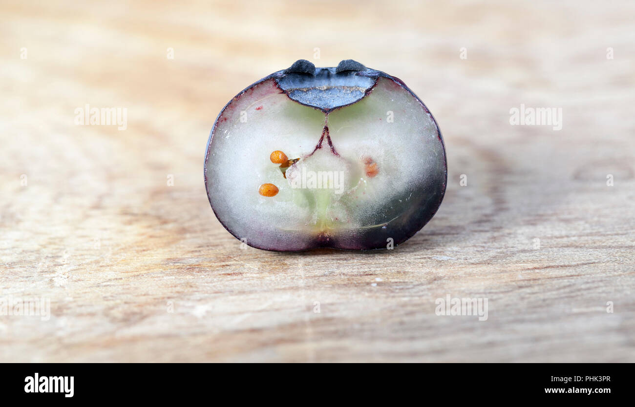 one ripe blueberry berry close-up cut in half and visible seeds and ...