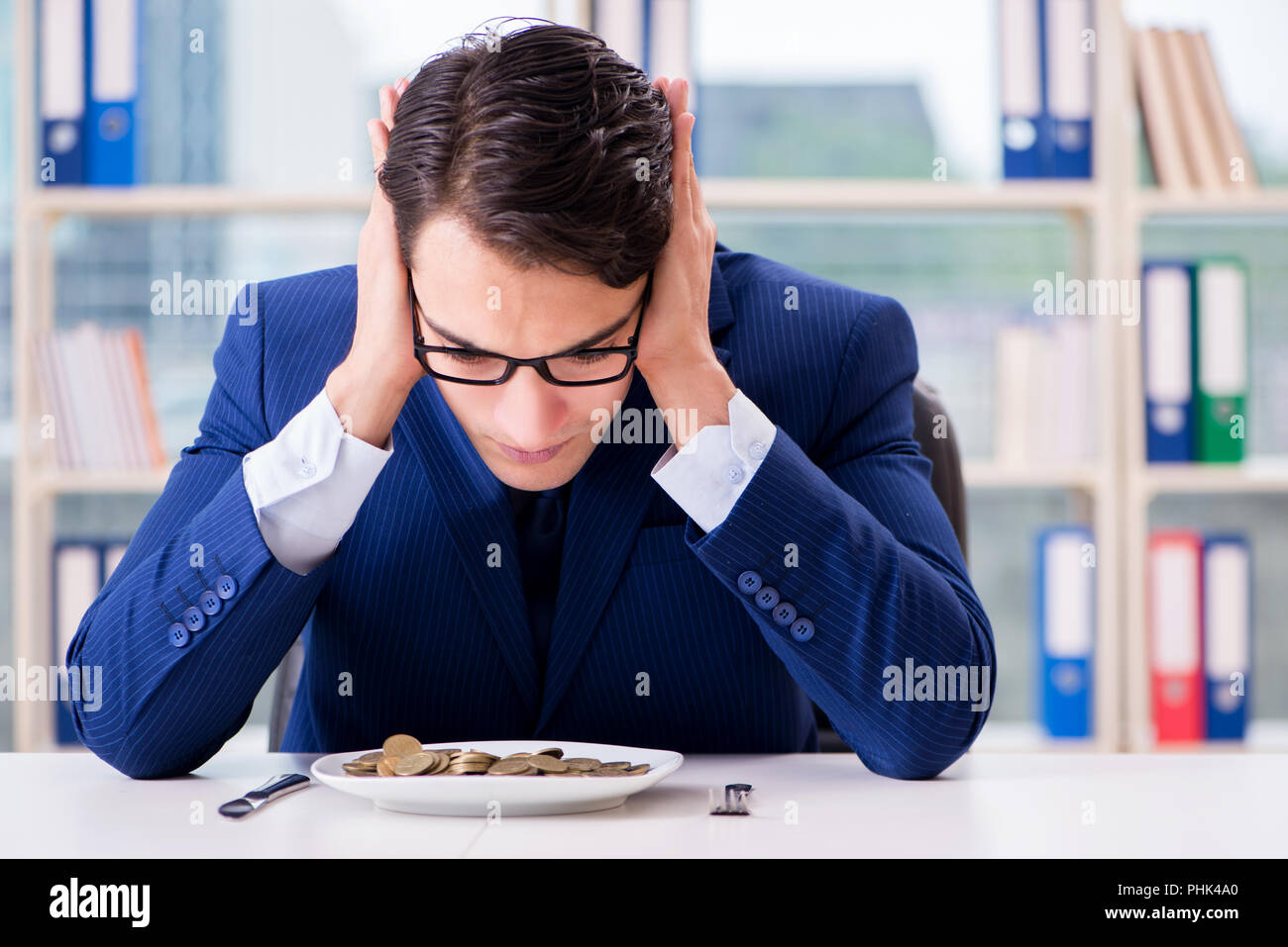Funny businessman eating gold coins in office Stock Photo - Alamy