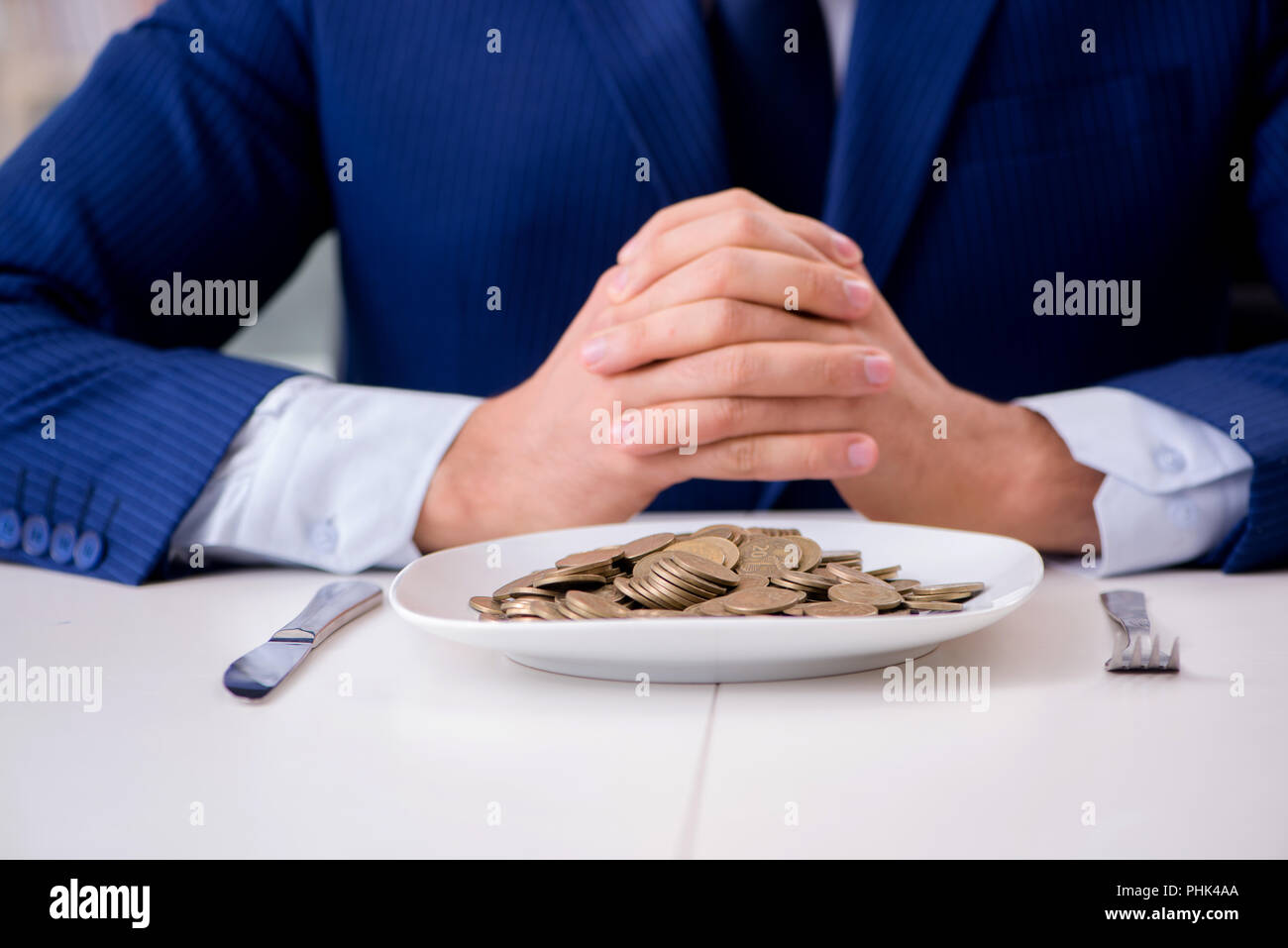 Funny businessman eating gold coins in office Stock Photo - Alamy