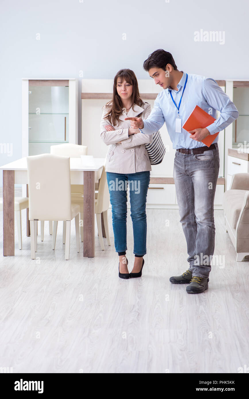 Salesman explaining to woman customer at furniture store Stock Photo ...