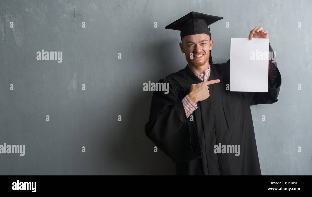 Young redhead man over grey grunge wall wearing graduate uniform ...