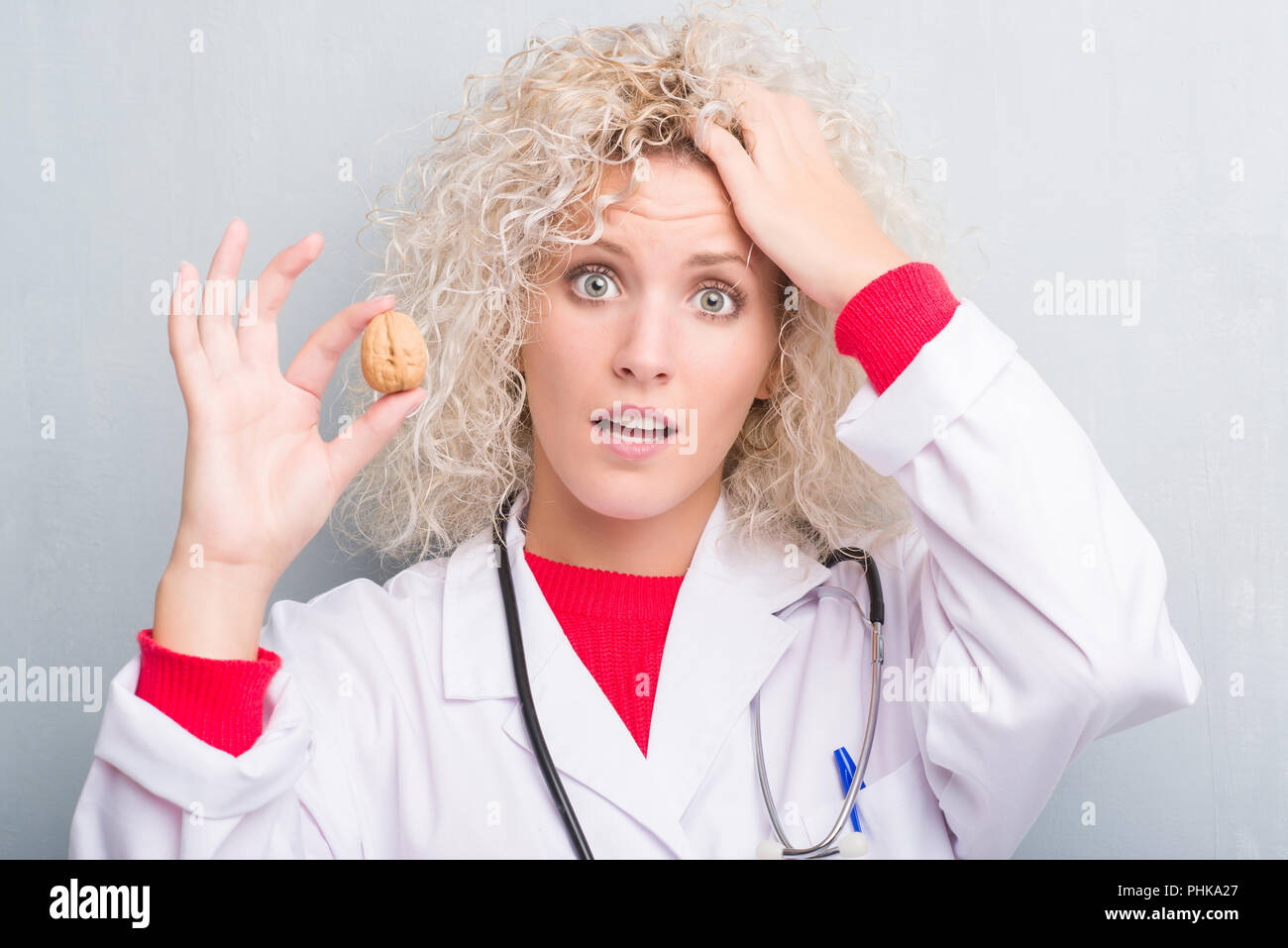 Young blonde nutritionist doctor woman over grunge grey wall holding ...