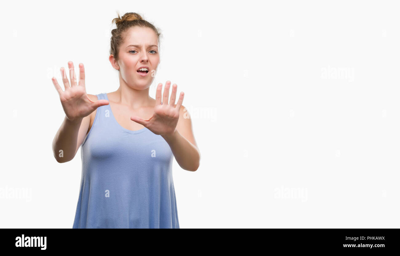 Young blonde woman afraid and terrified with fear expression stop ...