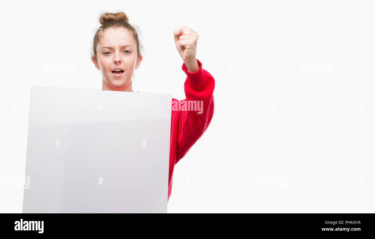 Young blonde woman holding advertising banner annoyed and frustrated ...