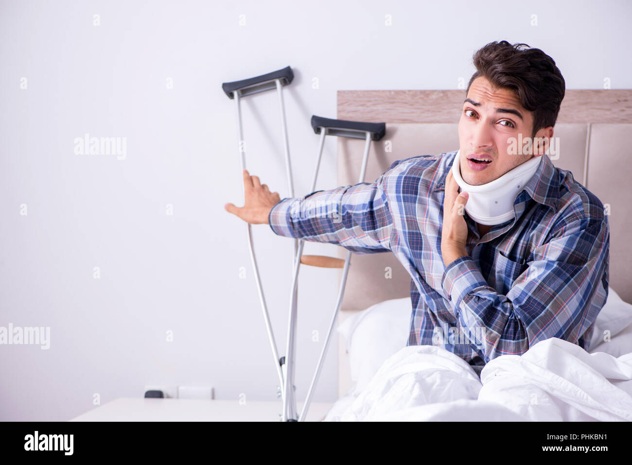 Injured man in bed at home with crutches Stock Photo - Alamy