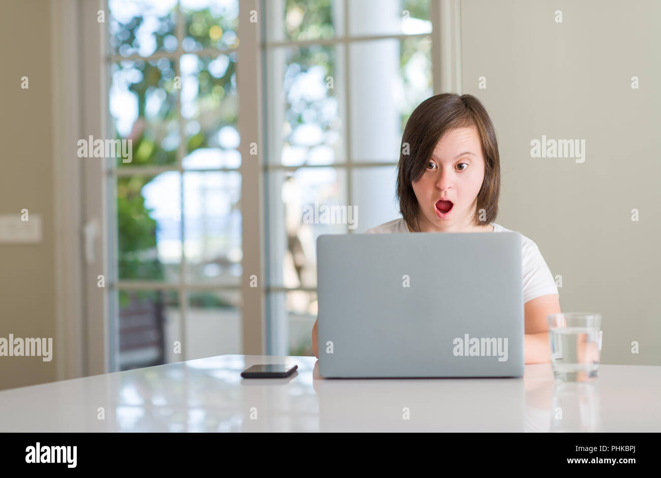 Down syndrome woman at home using computer laptop scared in shock with ...
