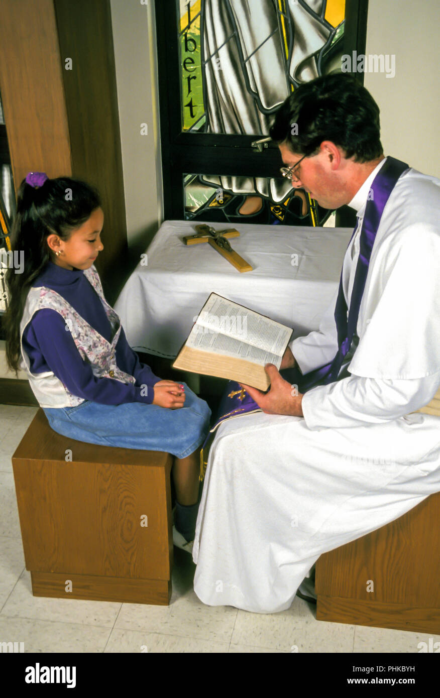 Catholic priest reading Bible to child during reconciliation. © Myrleen ...