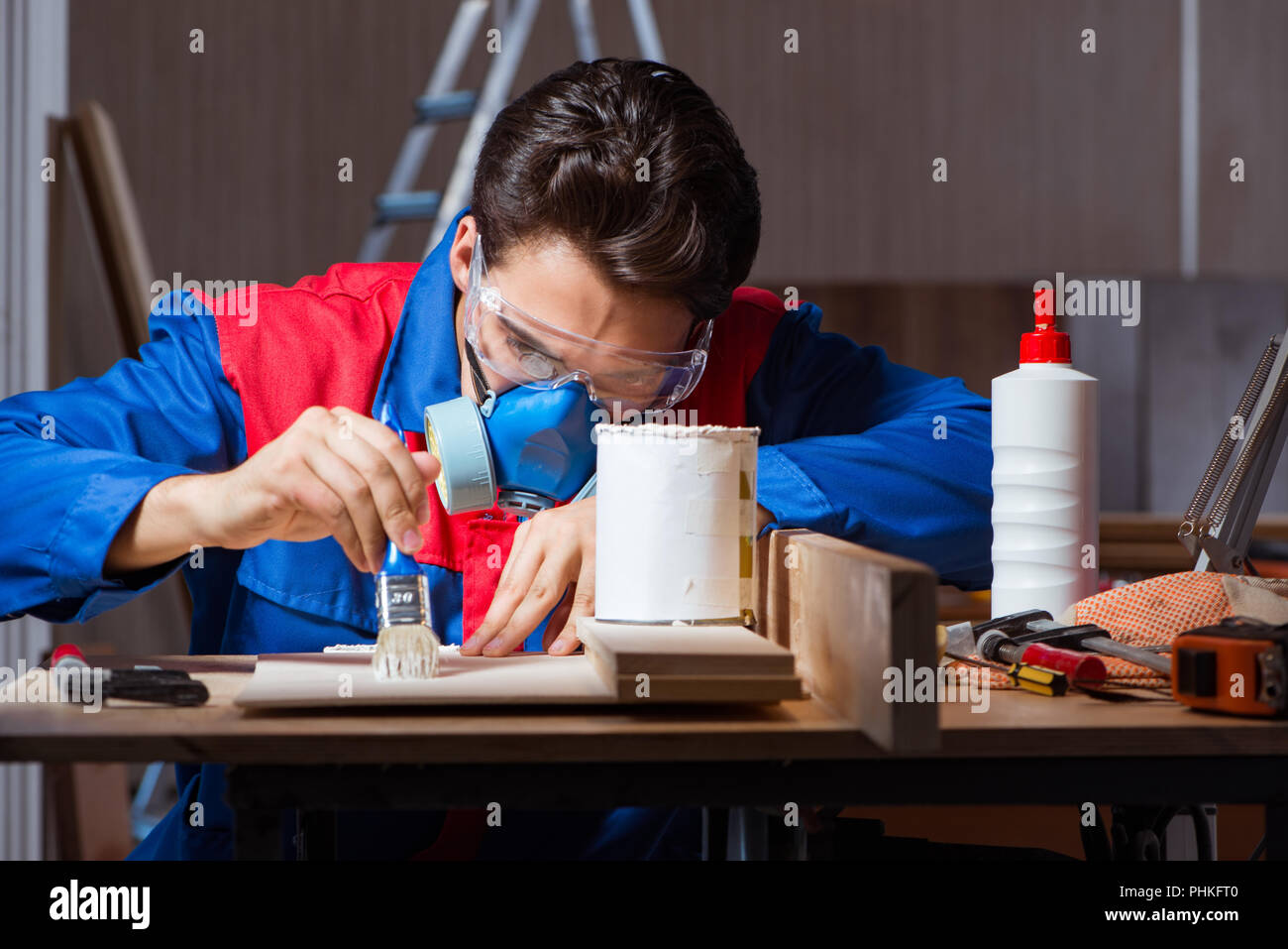 Young man gluing wood pieces together in DIY concept Stock Photo - Alamy