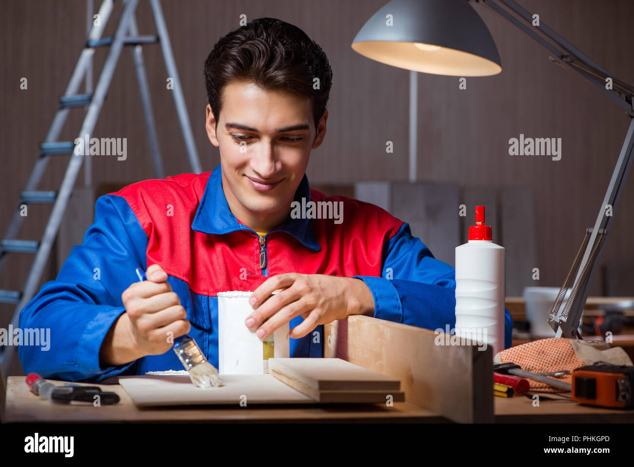 Young man gluing wood pieces together in DIY concept Stock Photo - Alamy