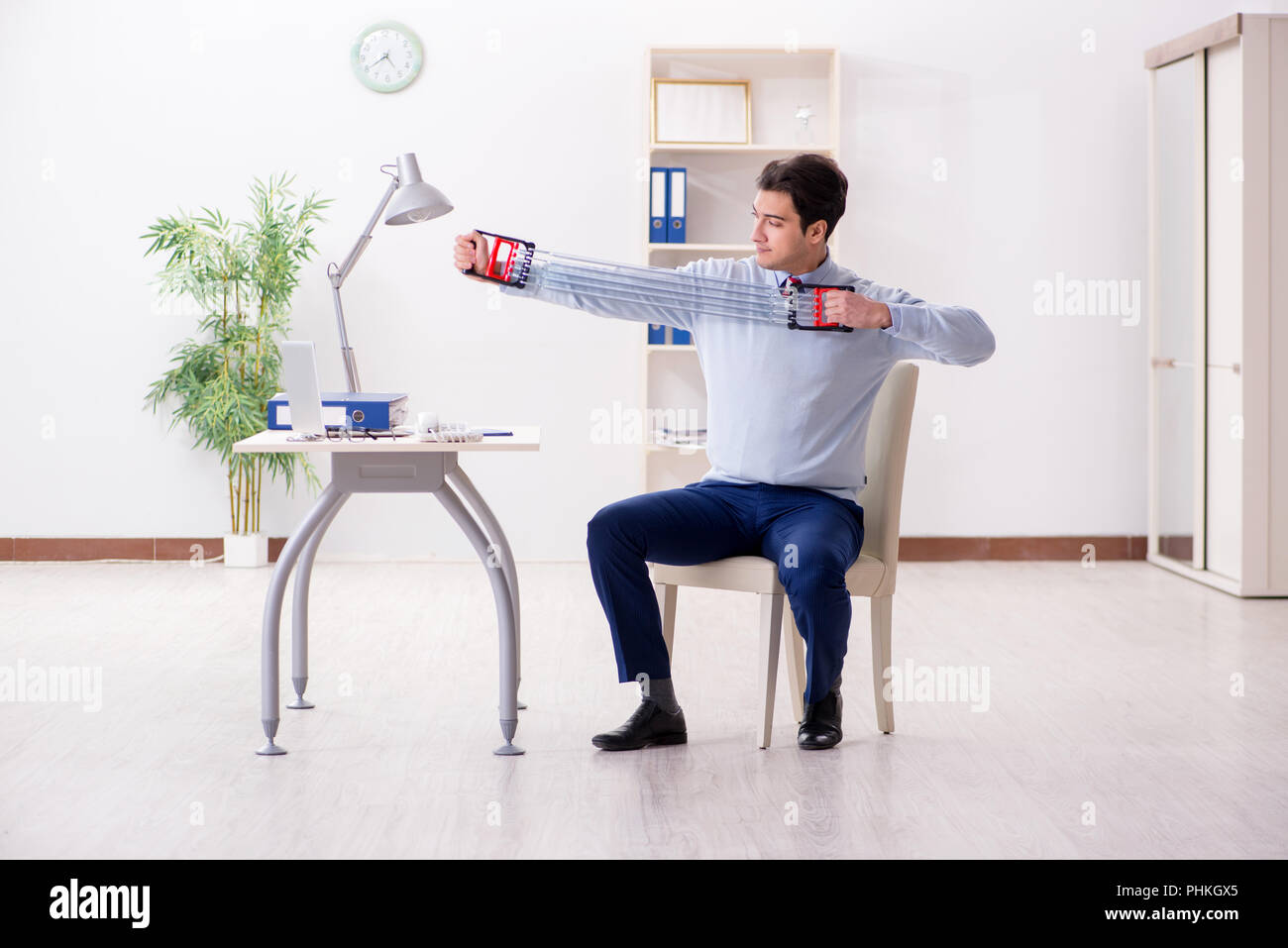 Man exercising with elastic band in office during lunch break Stock ...