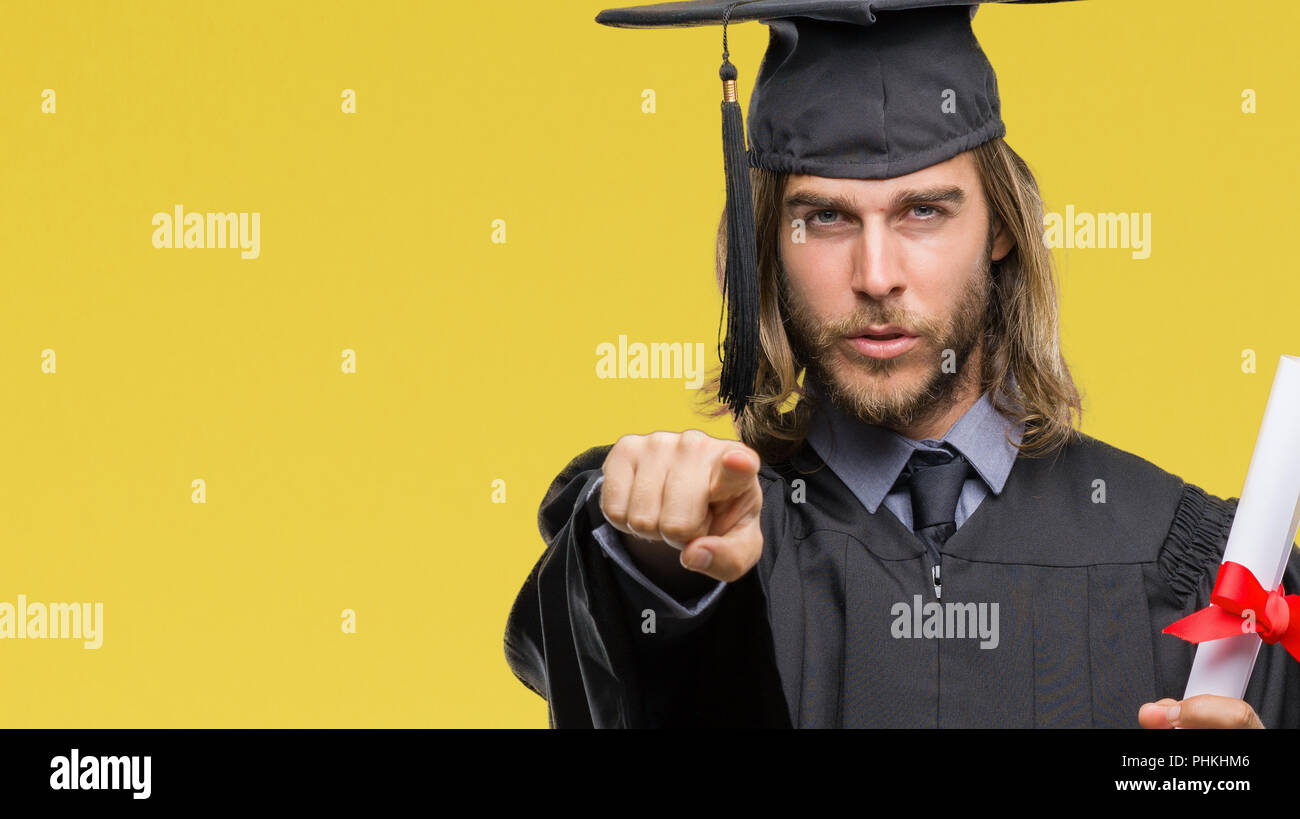 Young handsome graduate man with long hair holding degree over isolated ...