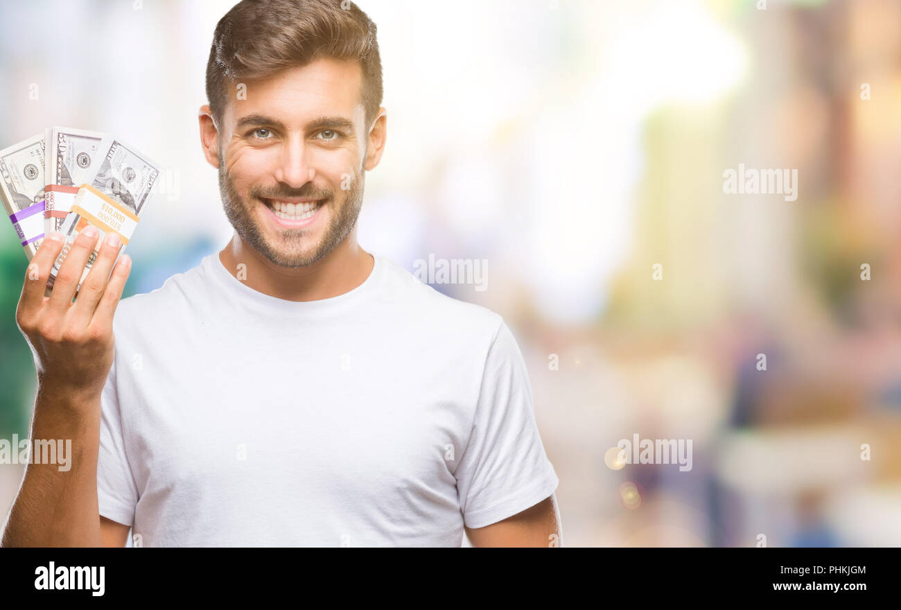 Young handsome man holding stack of dollars over isolated background ...