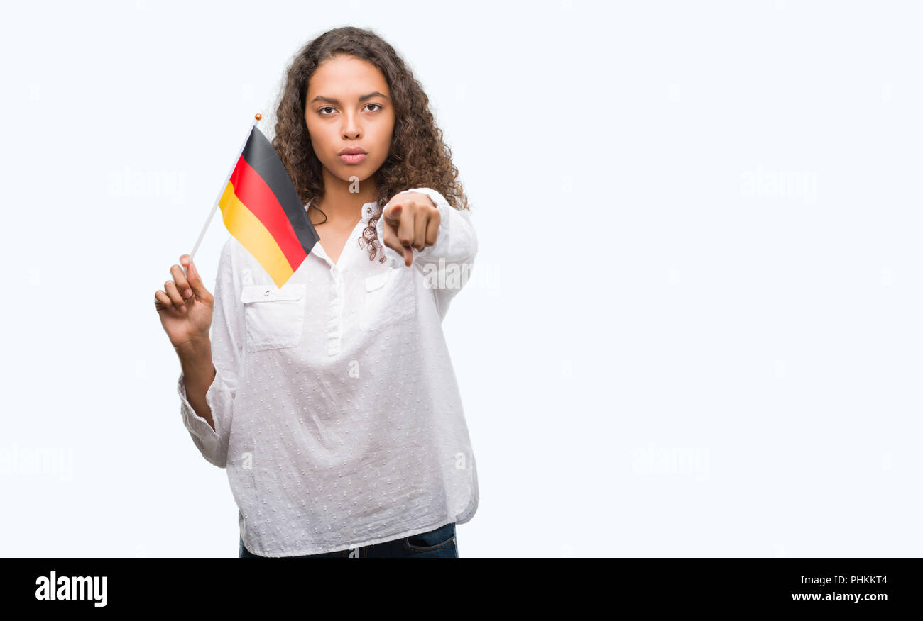 Young hispanic woman holding flag of Germany pointing with finger to ...
