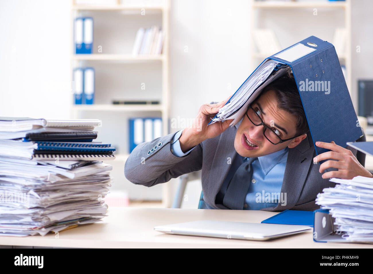 Overloaded with work employee under paperwork burden Stock Photo - Alamy