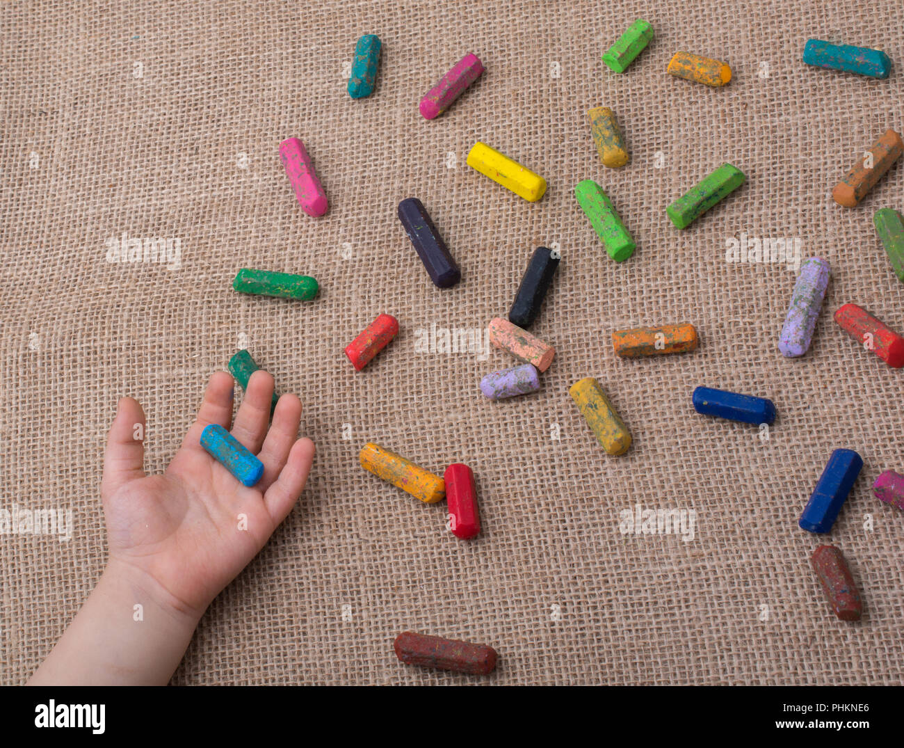 Used color crayons and a toddlers hand holding one Stock Photo - Alamy