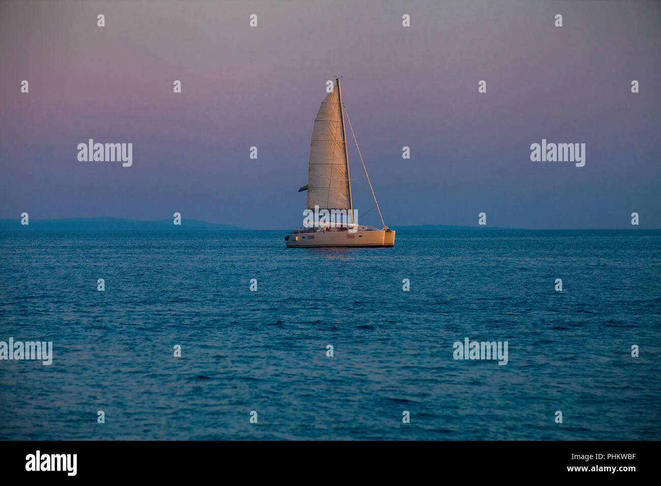Catamaran yacht sailing at sunset Stock Photo - Alamy