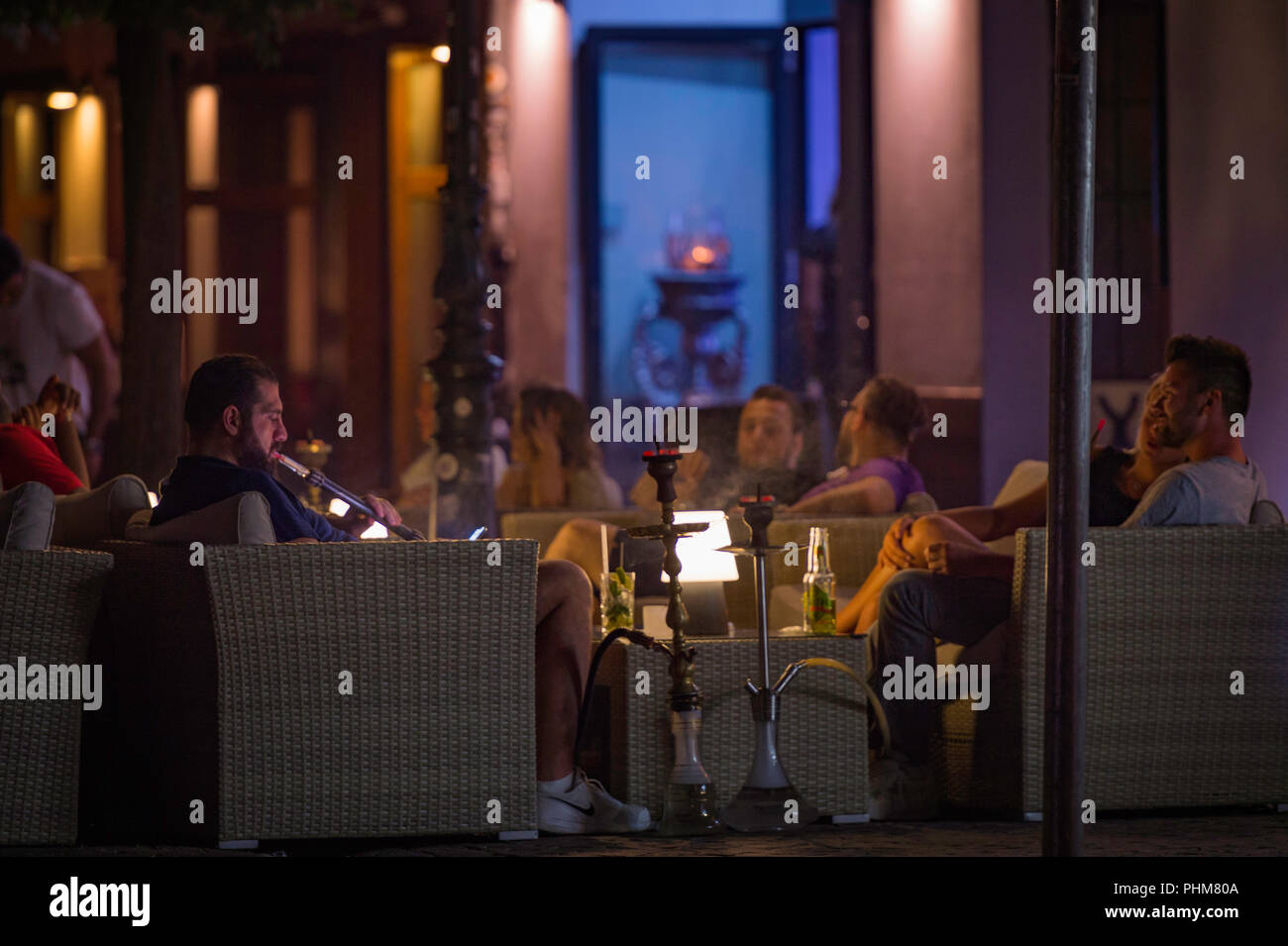 A group of people vaping on the street outside a cafe Stock Photo - Alamy
