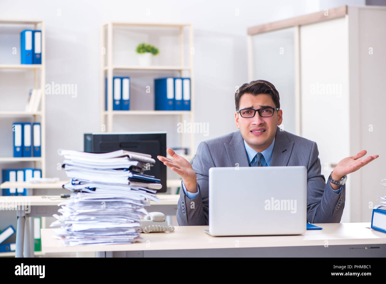 Overloaded with work employee under paperwork burden Stock Photo - Alamy