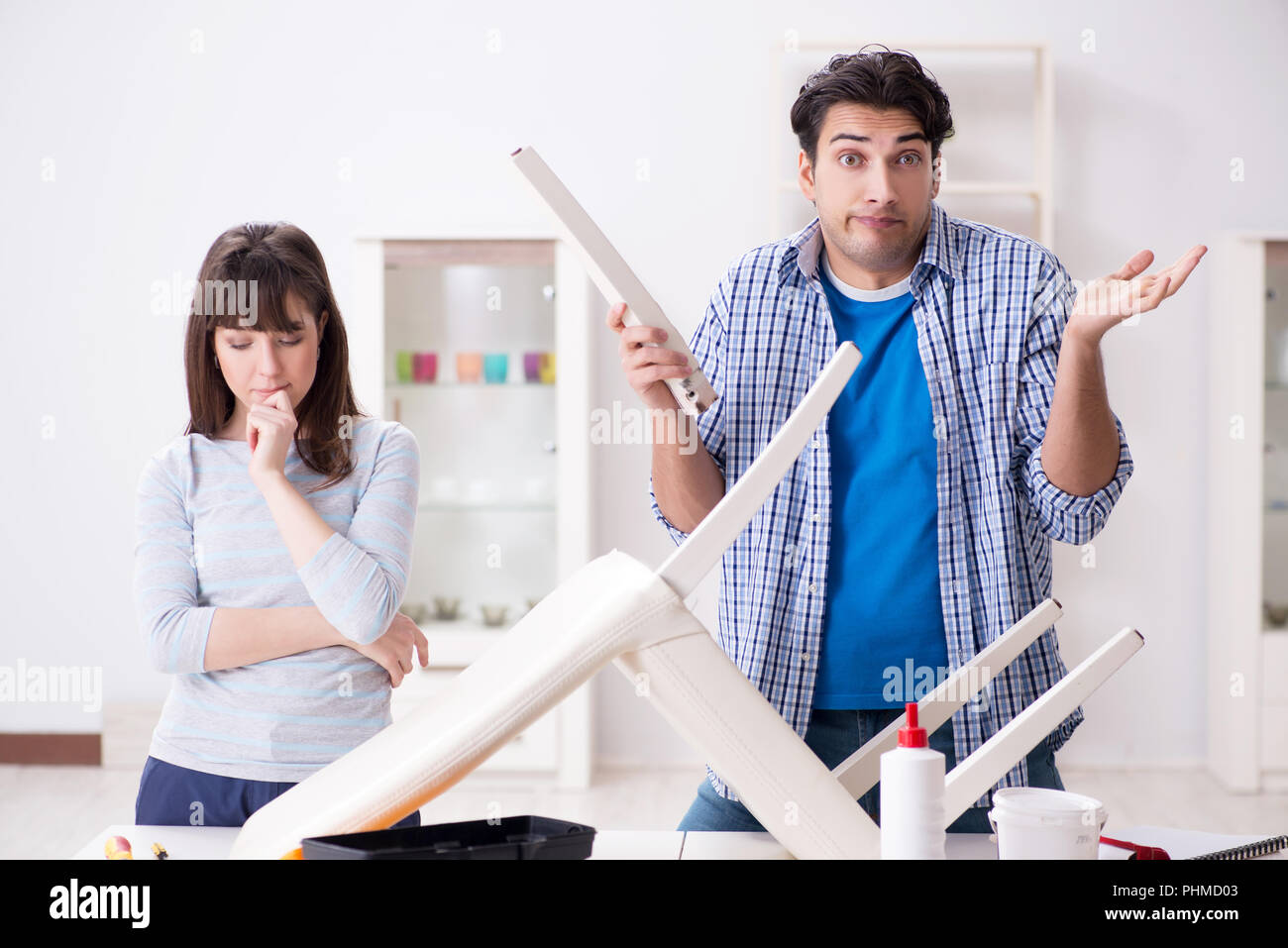 Wife helping husband to repair broken chair at home Stock Photo - Alamy