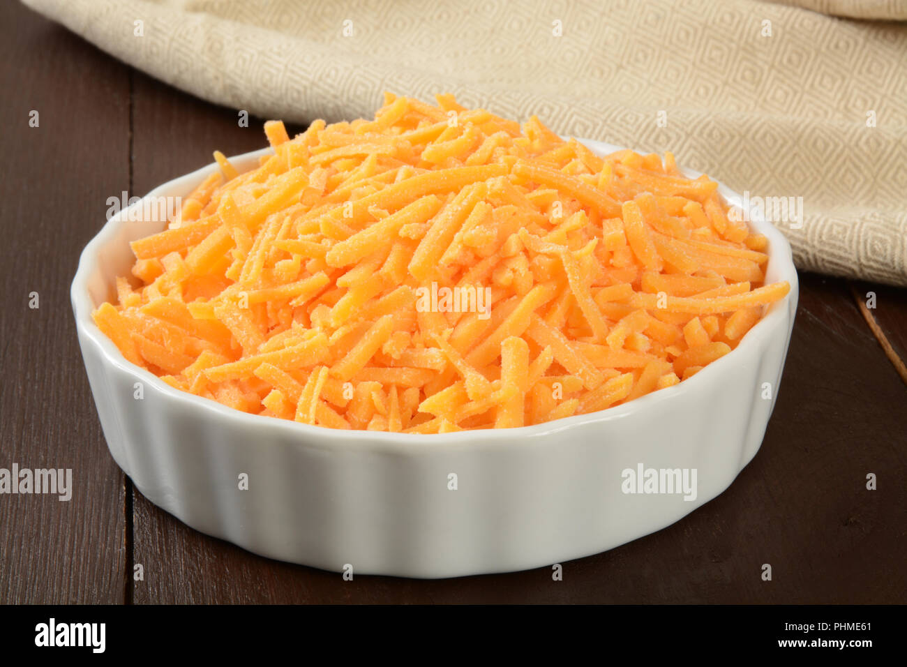 A bowl of grated sharp cheddar cheese on a rustic wooden counter Stock ...