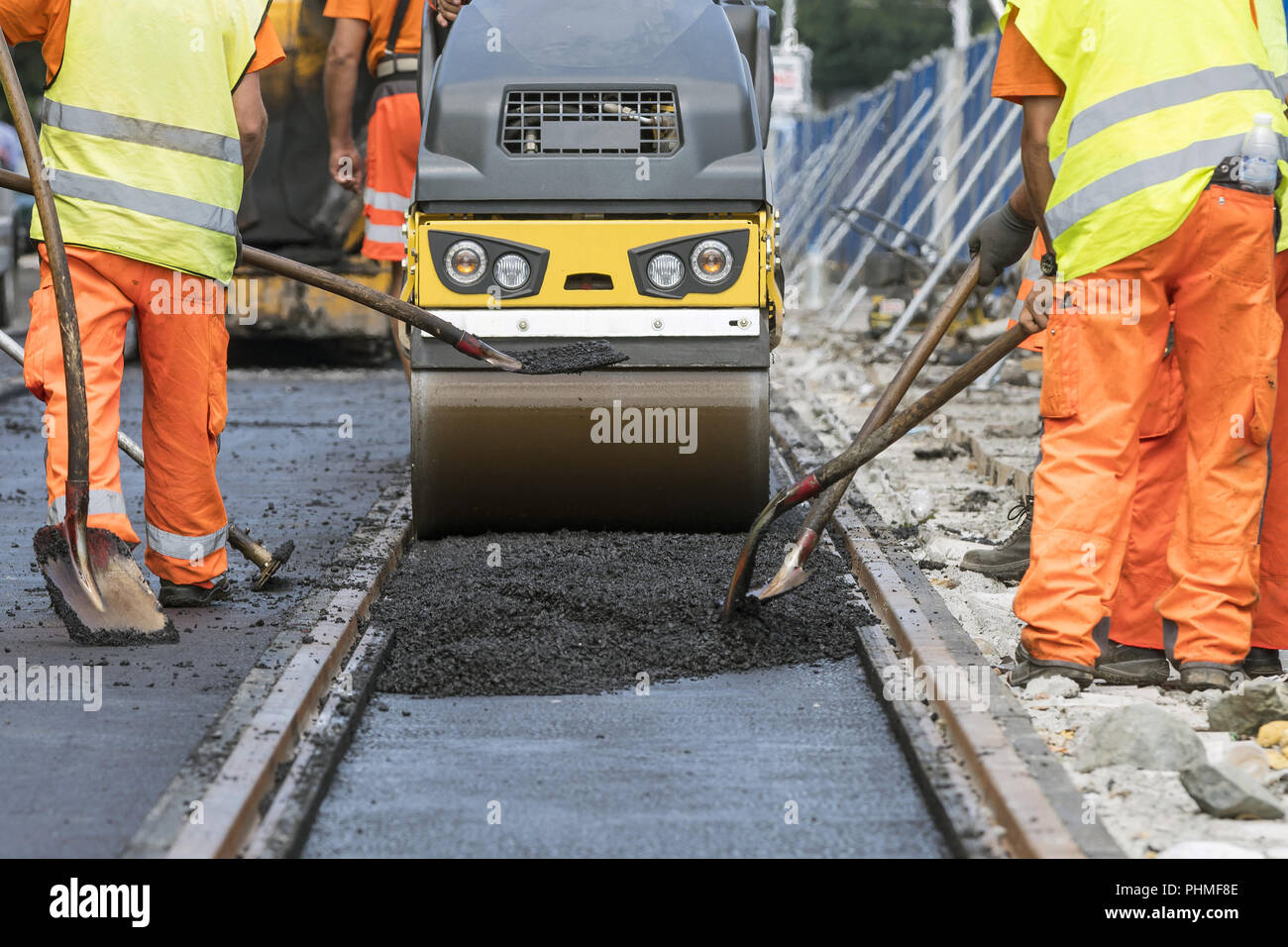 Steamroller workers construct asphalt road and railroad lines Stock ...
