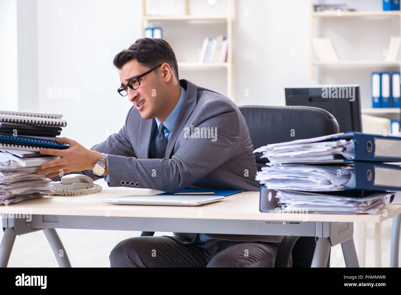 Overloaded with work employee under paperwork burden Stock Photo - Alamy