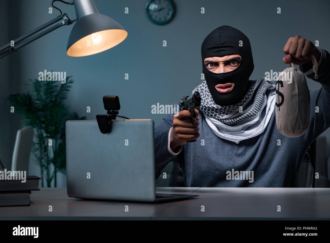 Terrorist burglar with gun working at computer Stock Photo - Alamy