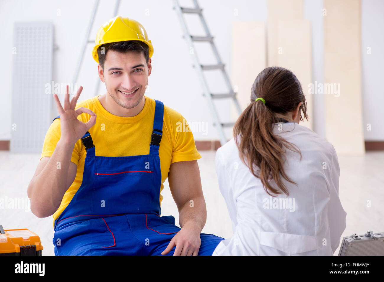 Doctor helping injured worker at construction site Stock Photo - Alamy
