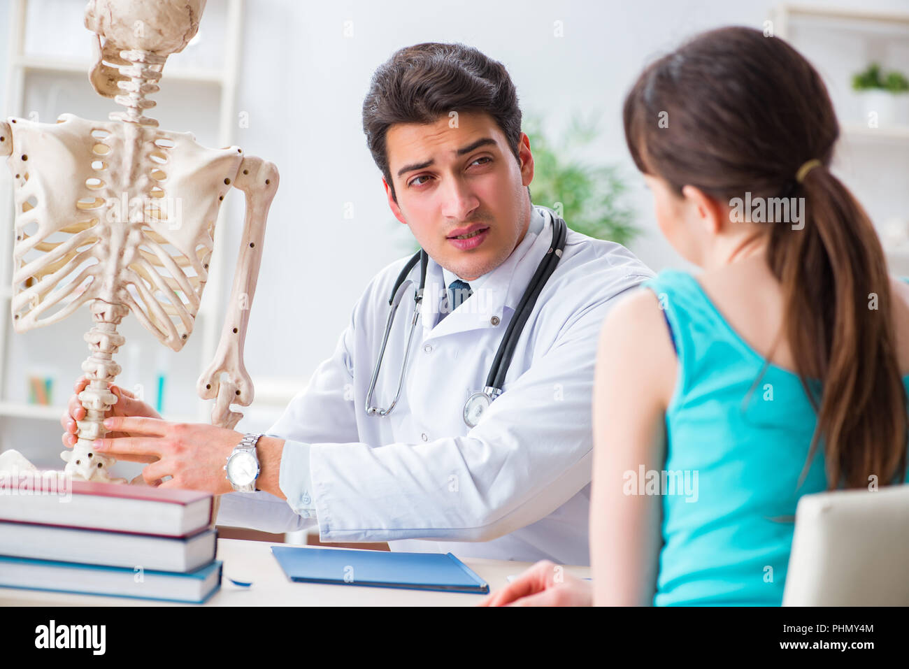 Doctor showing type of injury on skeleton to patient Stock Photo - Alamy