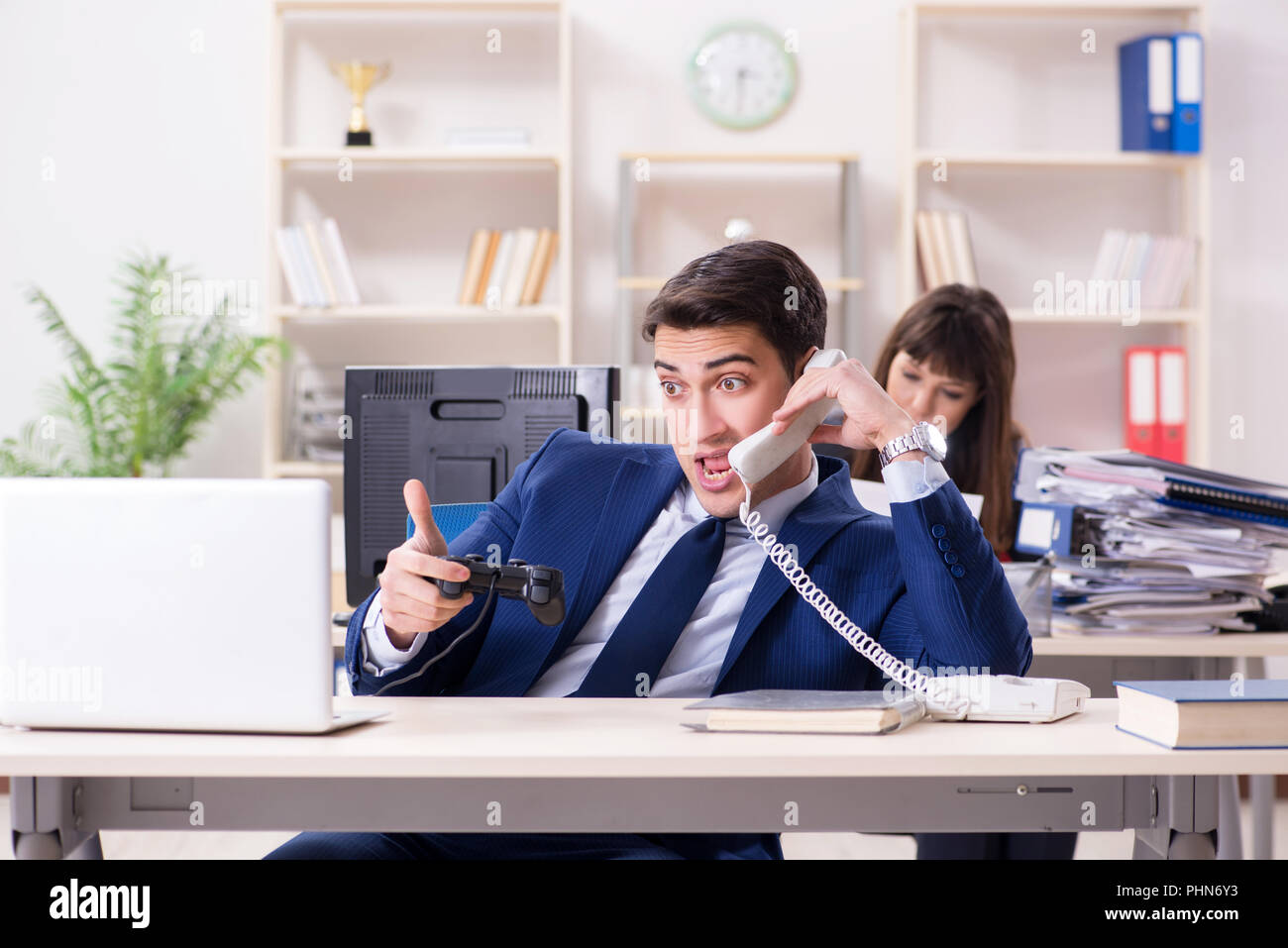 Man playing games in office while colleague is busy Stock Photo - Alamy