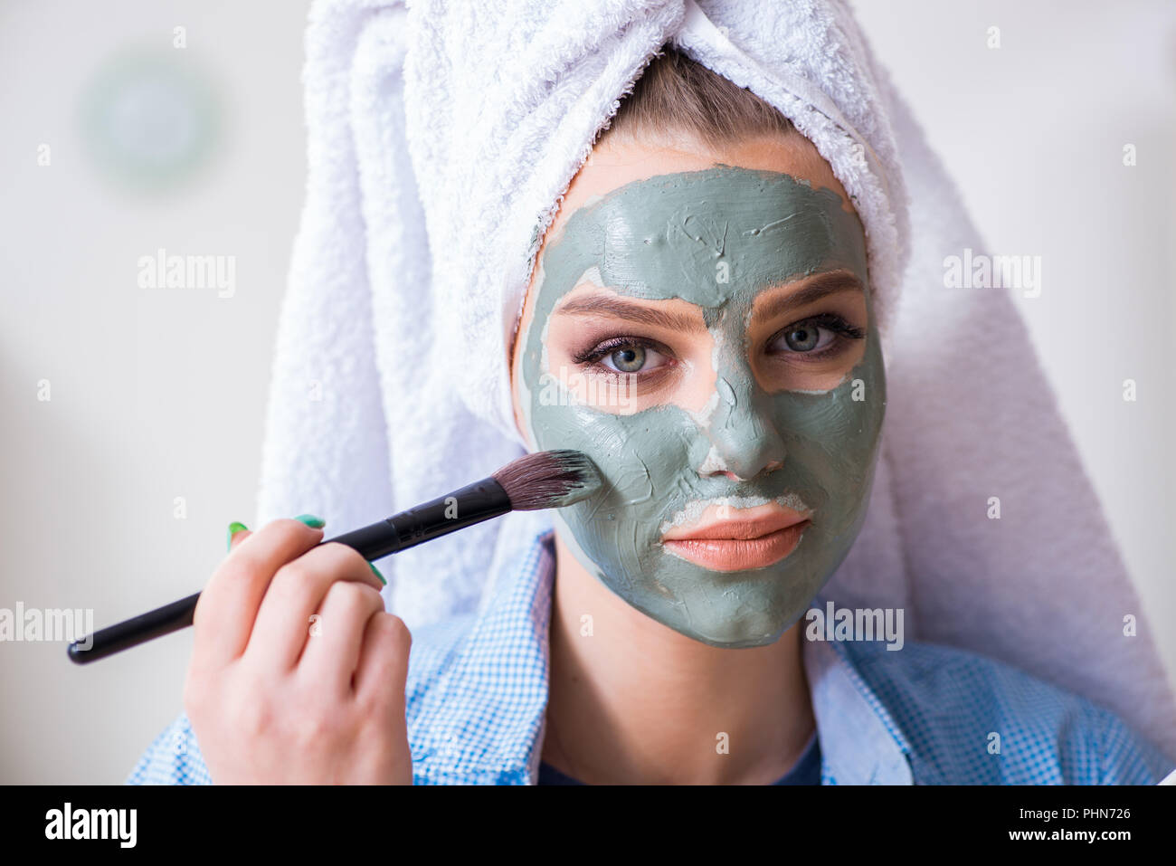 Woman applying clay mask with brush at home Stock Photo - Alamy