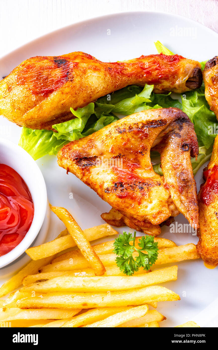 Grilled chicken wings,legs,chips and vegetables Stock Photo - Alamy