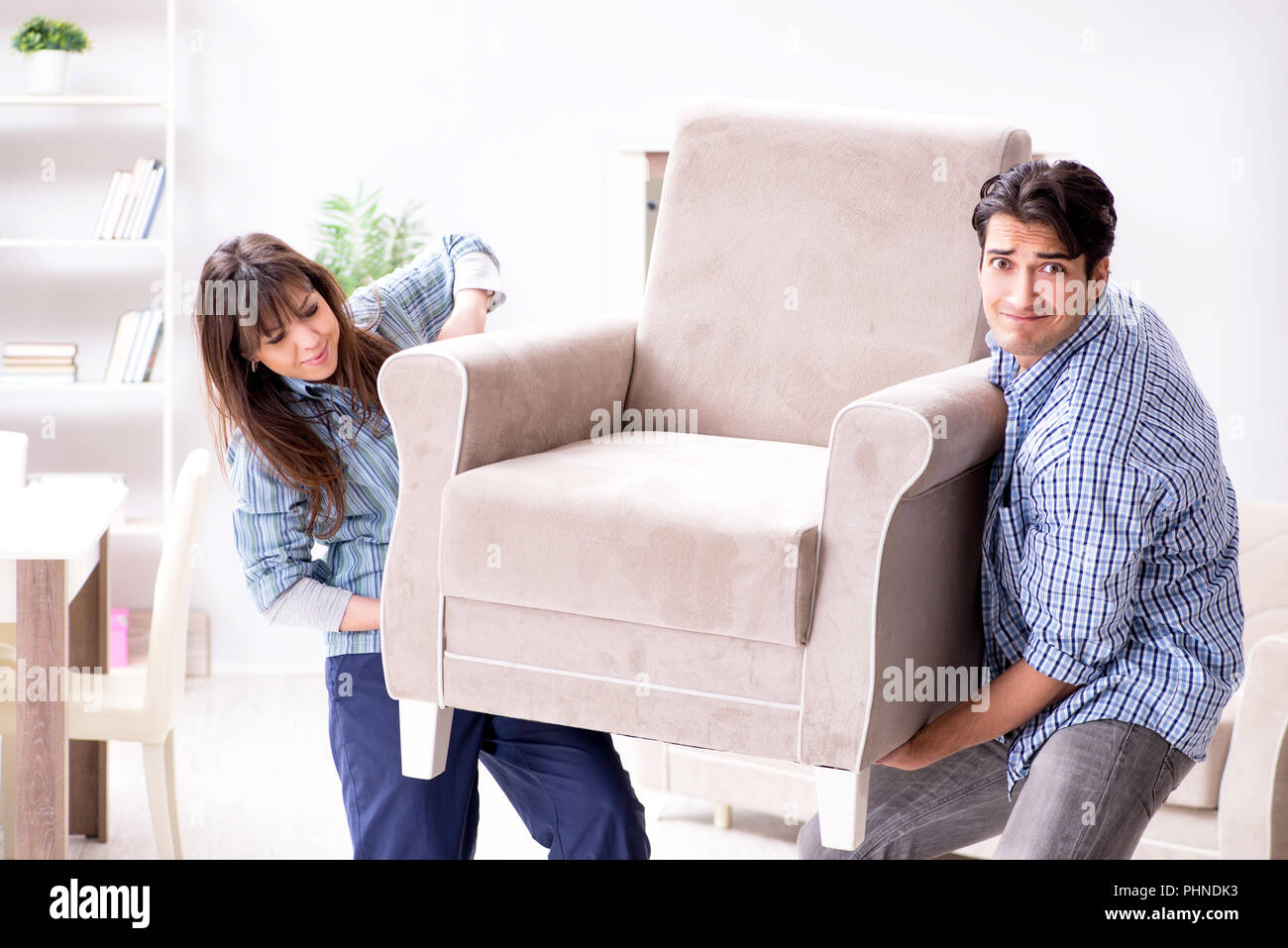 Man moving armchair in the living room Stock Photo - Alamy