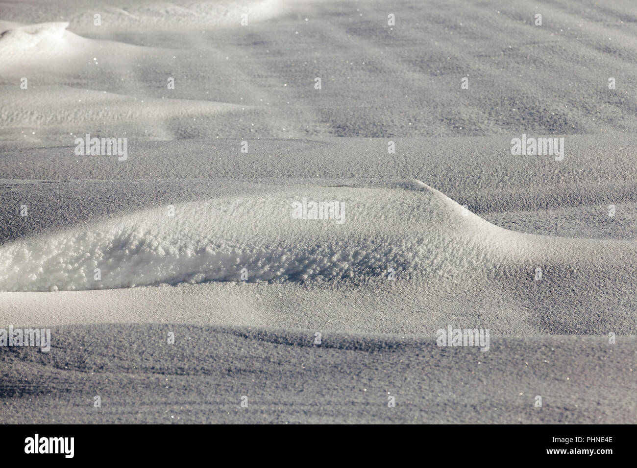 a large number of uneven and undulating snow drifts, illuminated by the ...