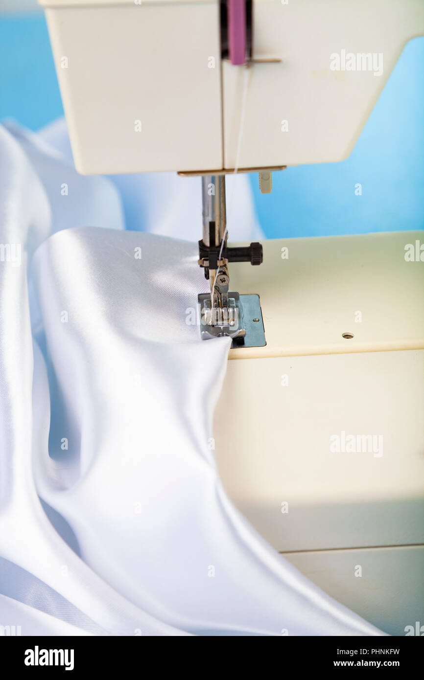 Sewing machine and white satin fabric close-up Stock Photo - Alamy