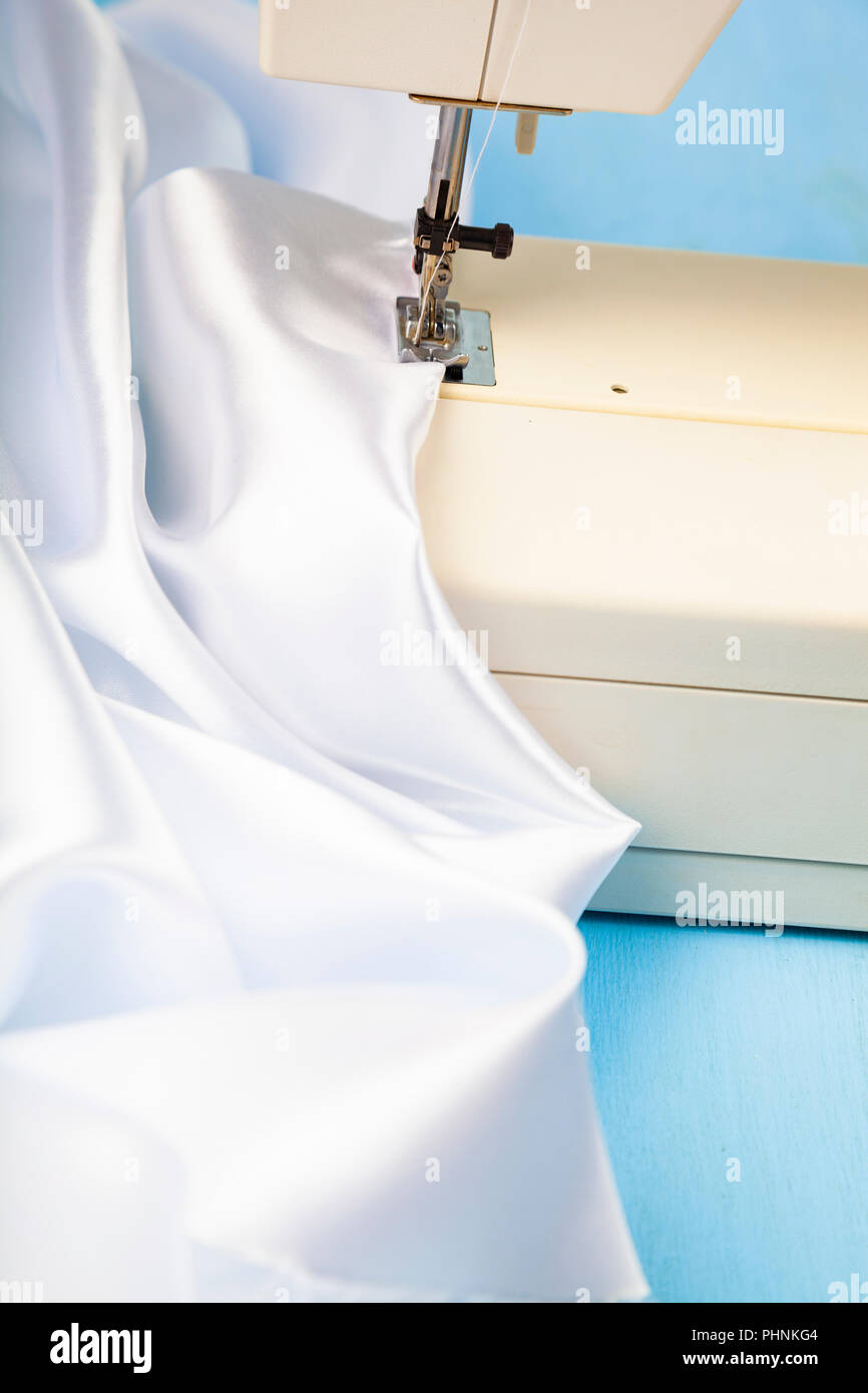 Sewing machine and white satin fabric close-up Stock Photo - Alamy