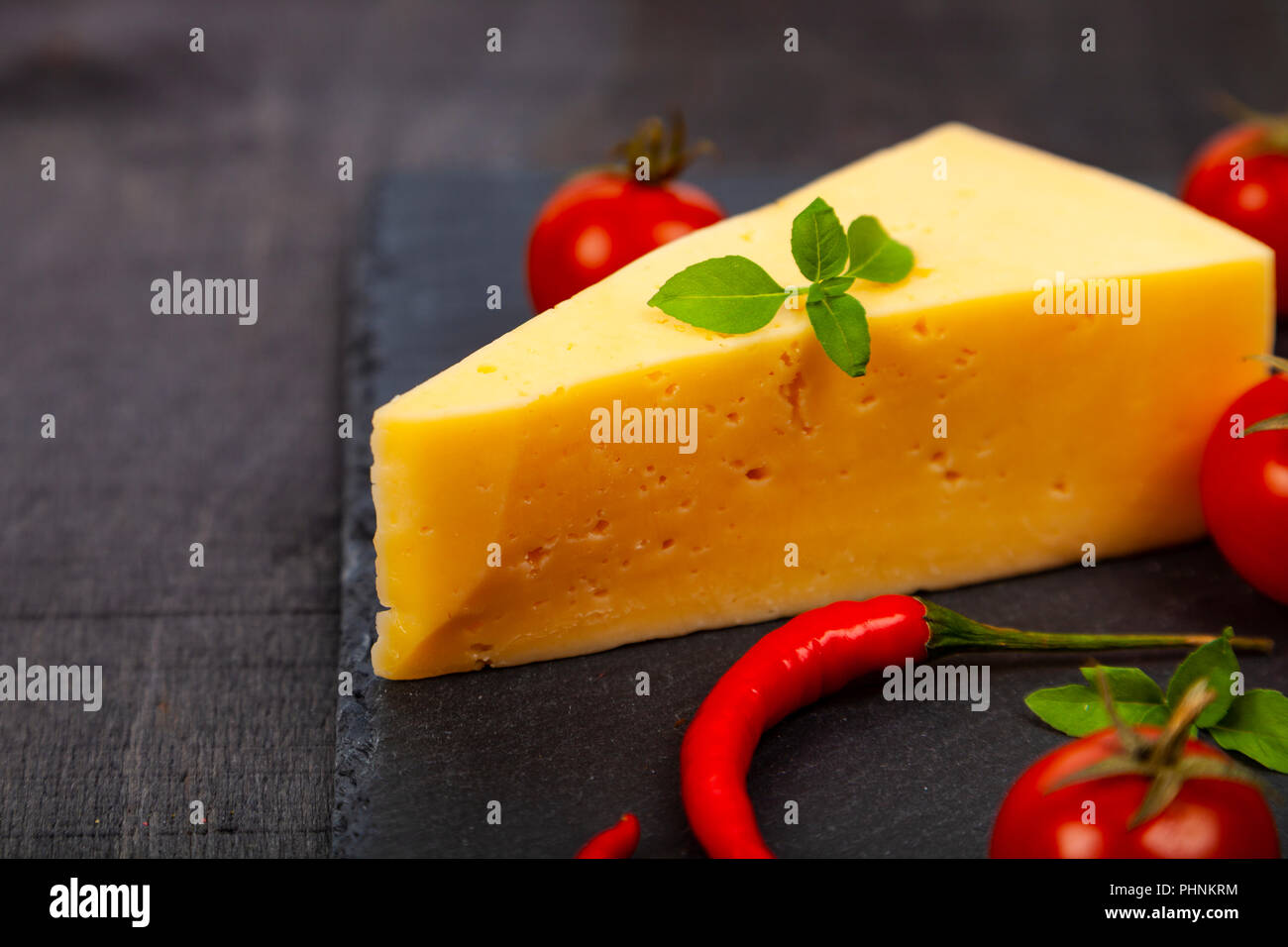 Cheese, cherry tomatoes and basil on a dark background Stock Photo - Alamy