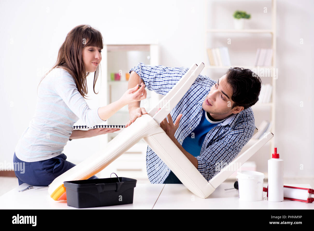 Wife helping husband to repair broken chair at home Stock Photo - Alamy