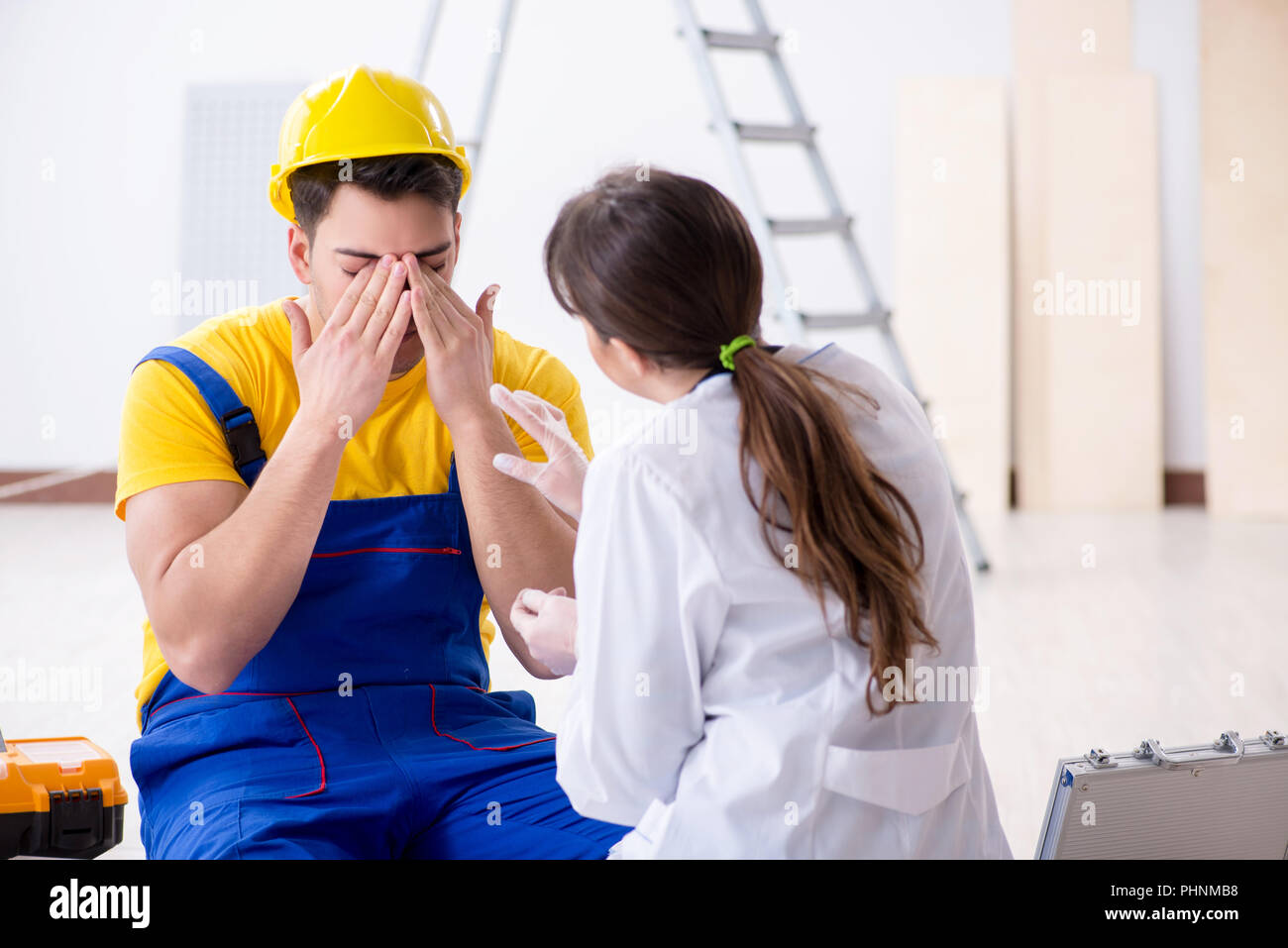 Doctor helping injured worker at construction site Stock Photo - Alamy